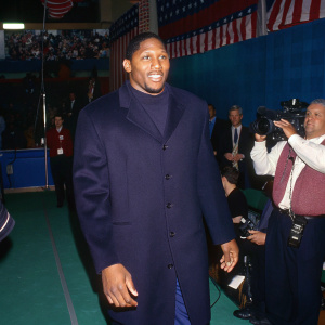 Ray Lewis, wearing a navy blazer, smiling confidently at a press ...